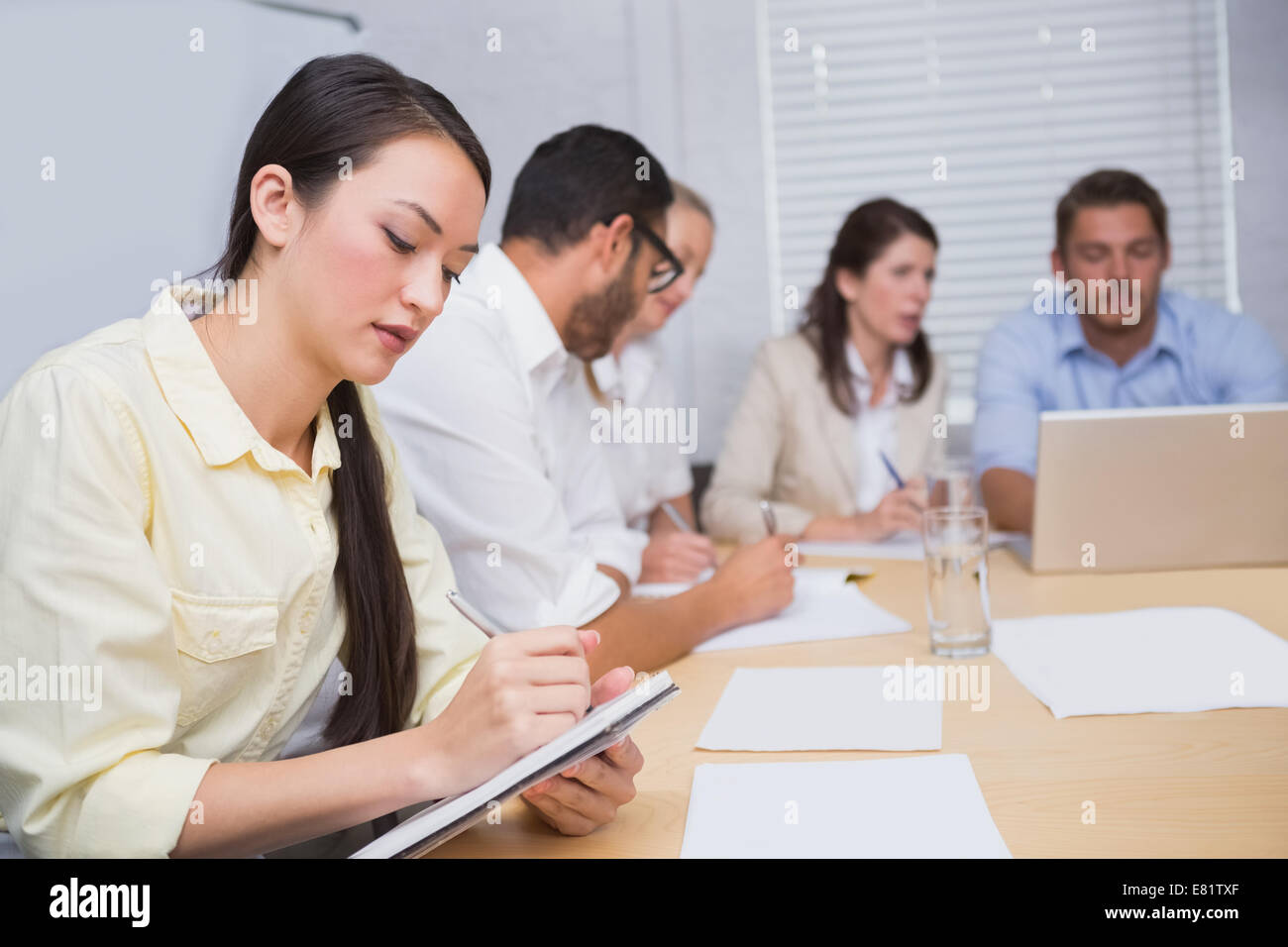 Woman taking notes while colleagues are talking behind her Stock Photo ...