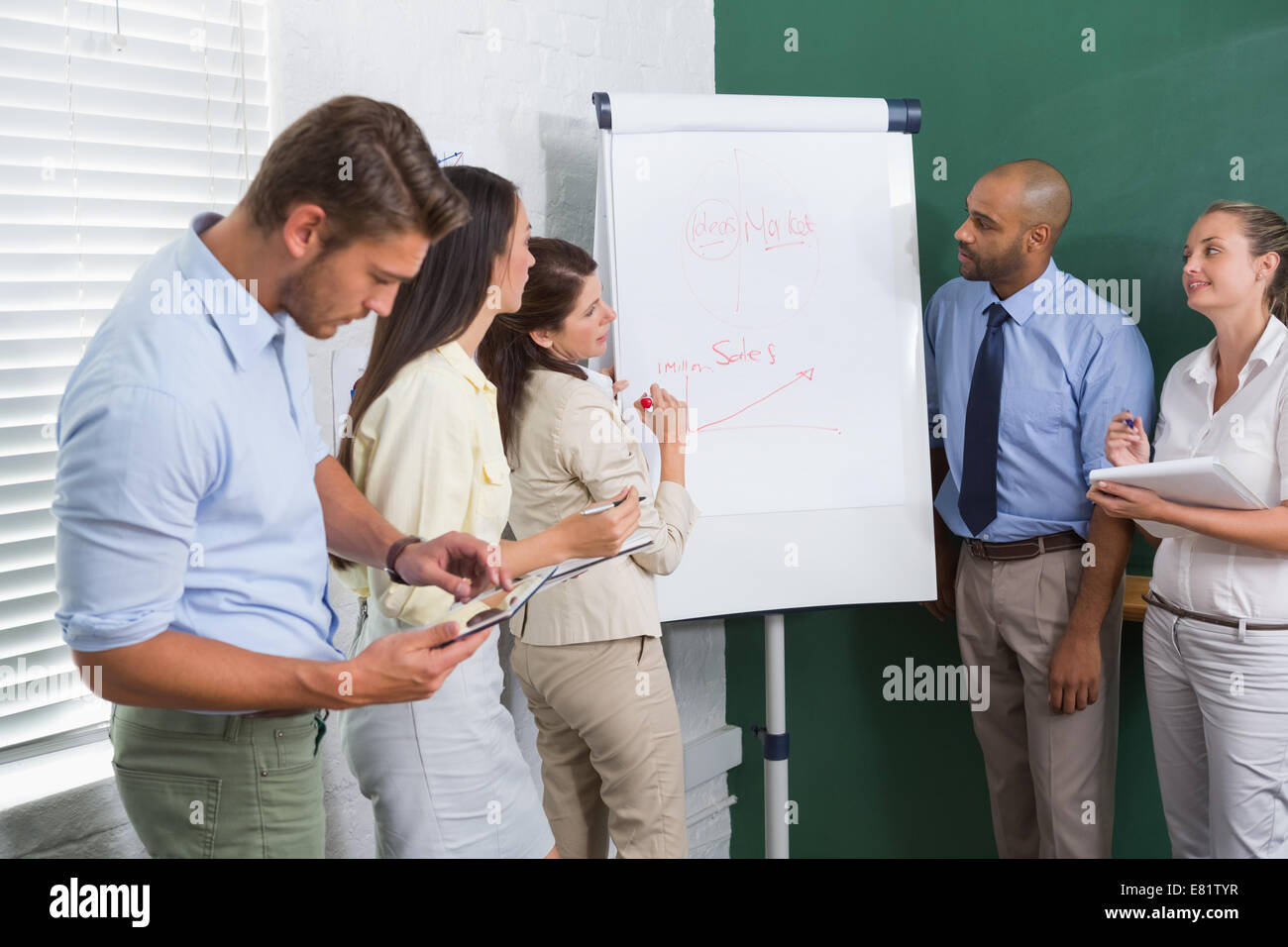 Businesswoman presenting to the team taking notes Stock Photo - Alamy