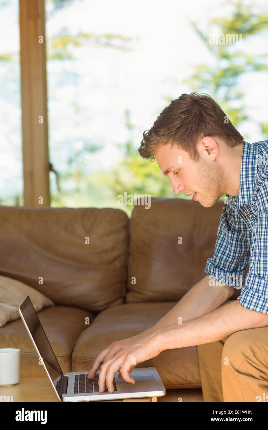Young man using laptop on his couch Stock Photo - Alamy