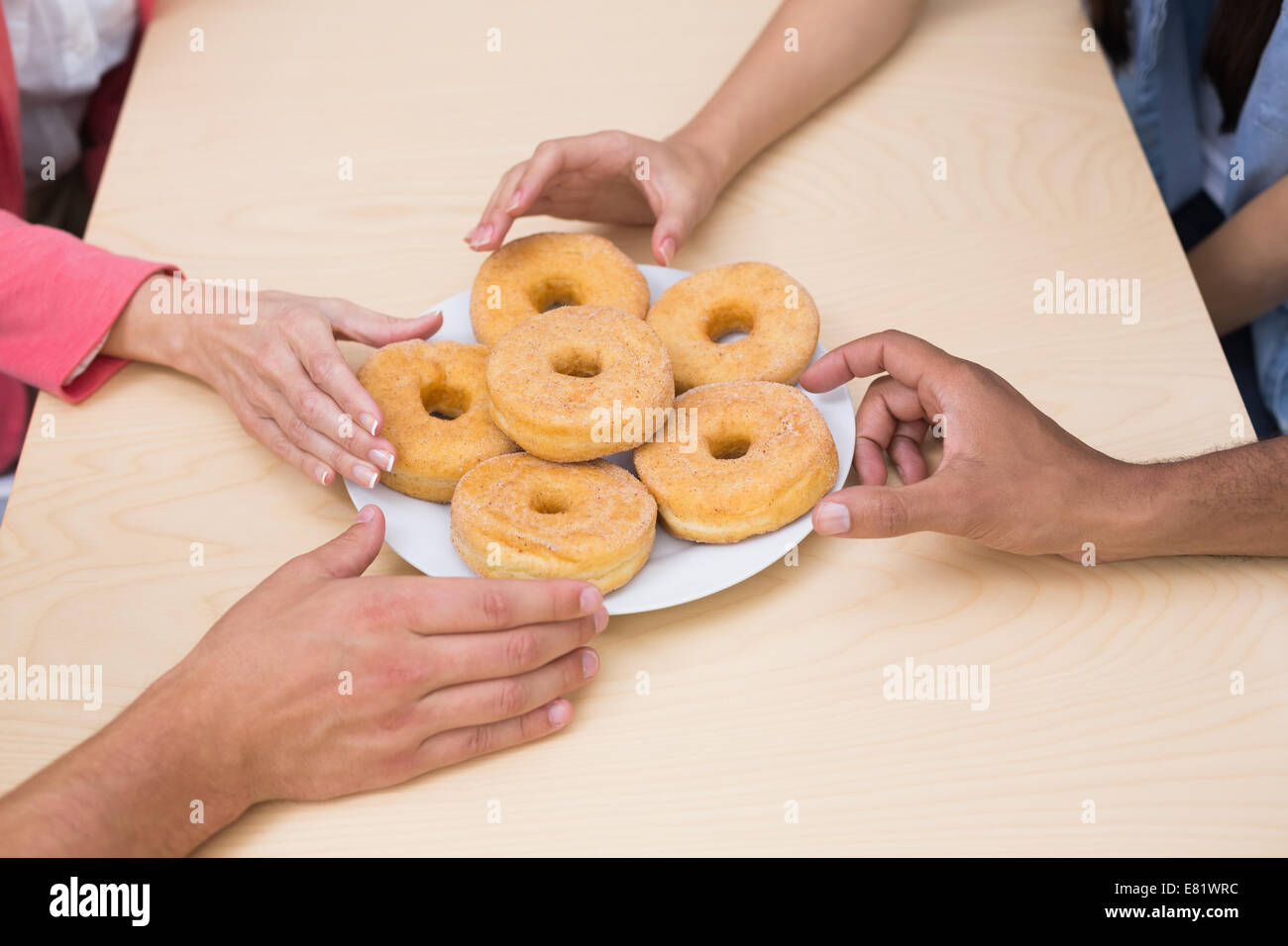 Business team reaching for doughnuts on table Stock Photo - Alamy