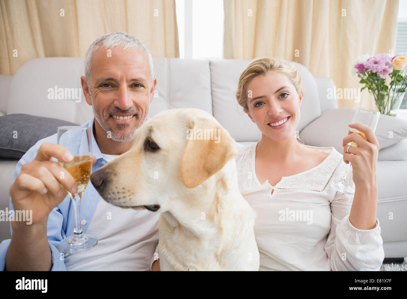 Happy couple with their pet dog drinking champagne Stock Photo - Alamy