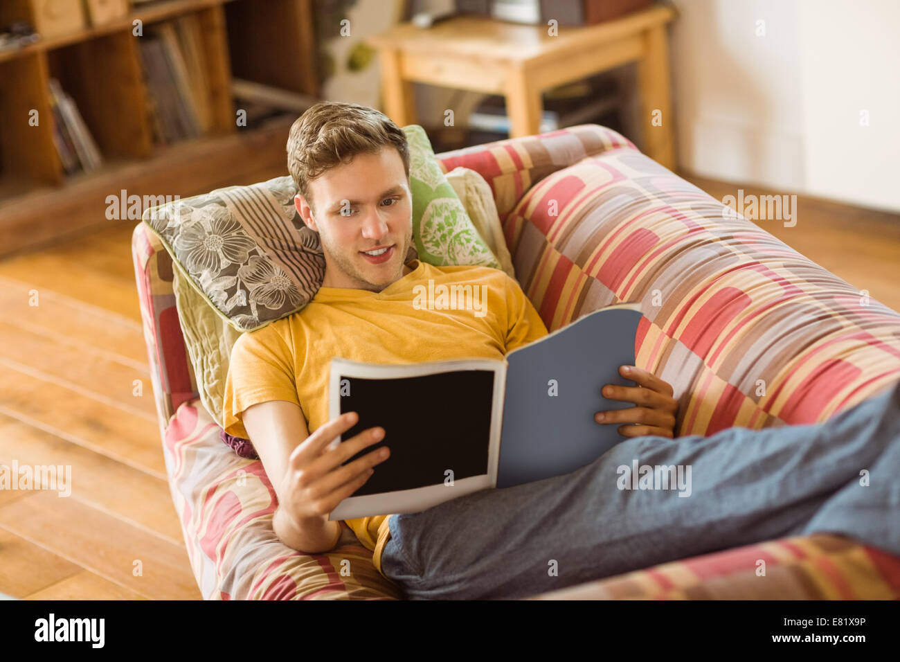 Young man reading magazine on his couch Stock Photo - Alamy