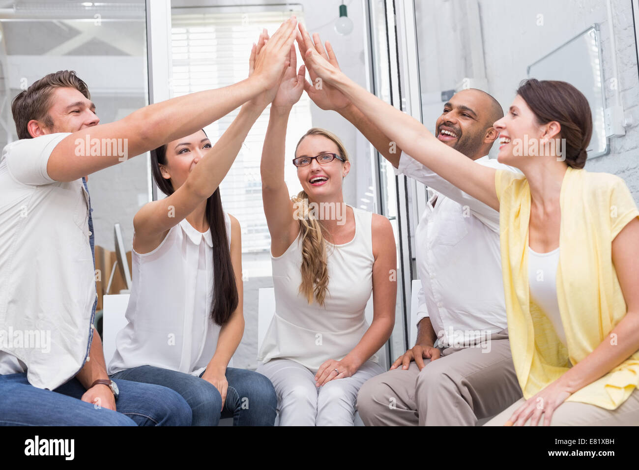 Happy business team high fiving Stock Photo - Alamy