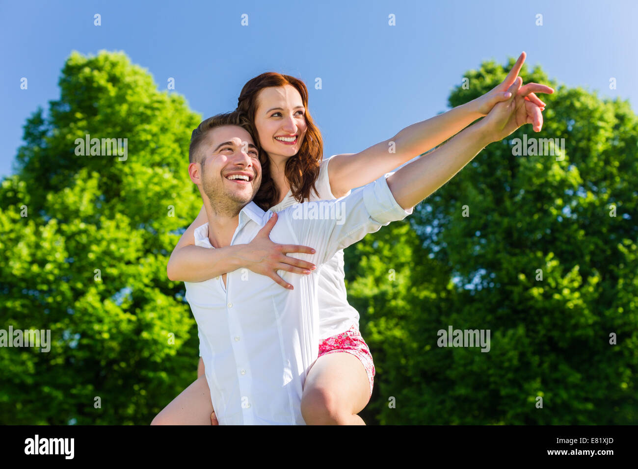 Man carrying woman piggyback in park Stock Photo - Alamy