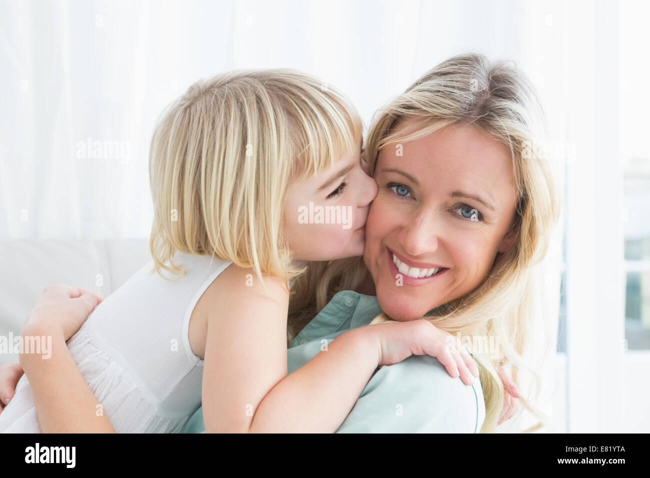 Mother sitting on the couch with her daughter kissing her cheek Stock ...