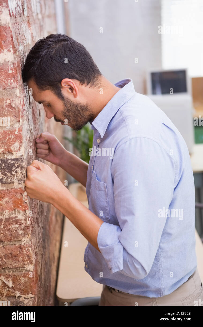Thoughtful young businessman standing against the wall Stock Photo - Alamy