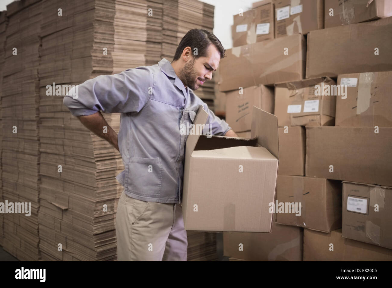Worker carrying box in warehouse Stock Photo - Alamy