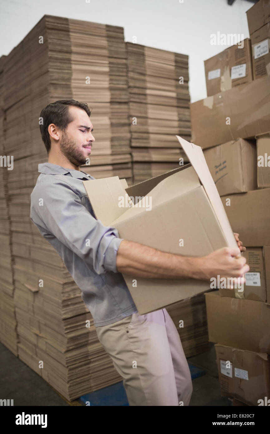Worker carrying box in warehouse Stock Photo - Alamy