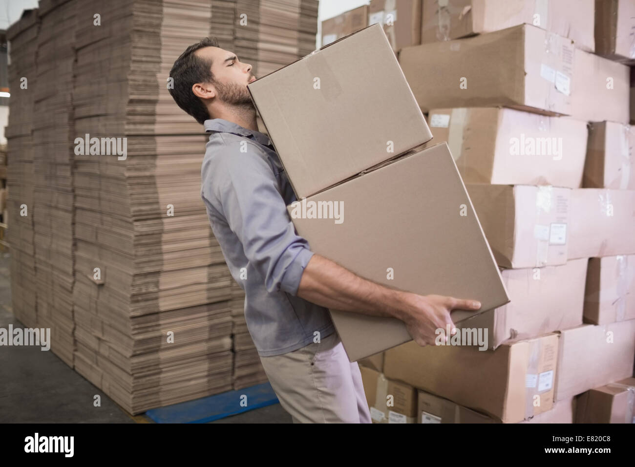 Worker carrying boxes in warehouse Stock Photo - Alamy