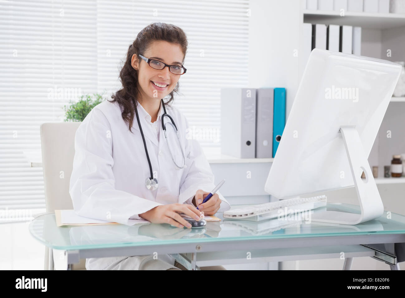Smiling vet writing and using computer Stock Photo - Alamy