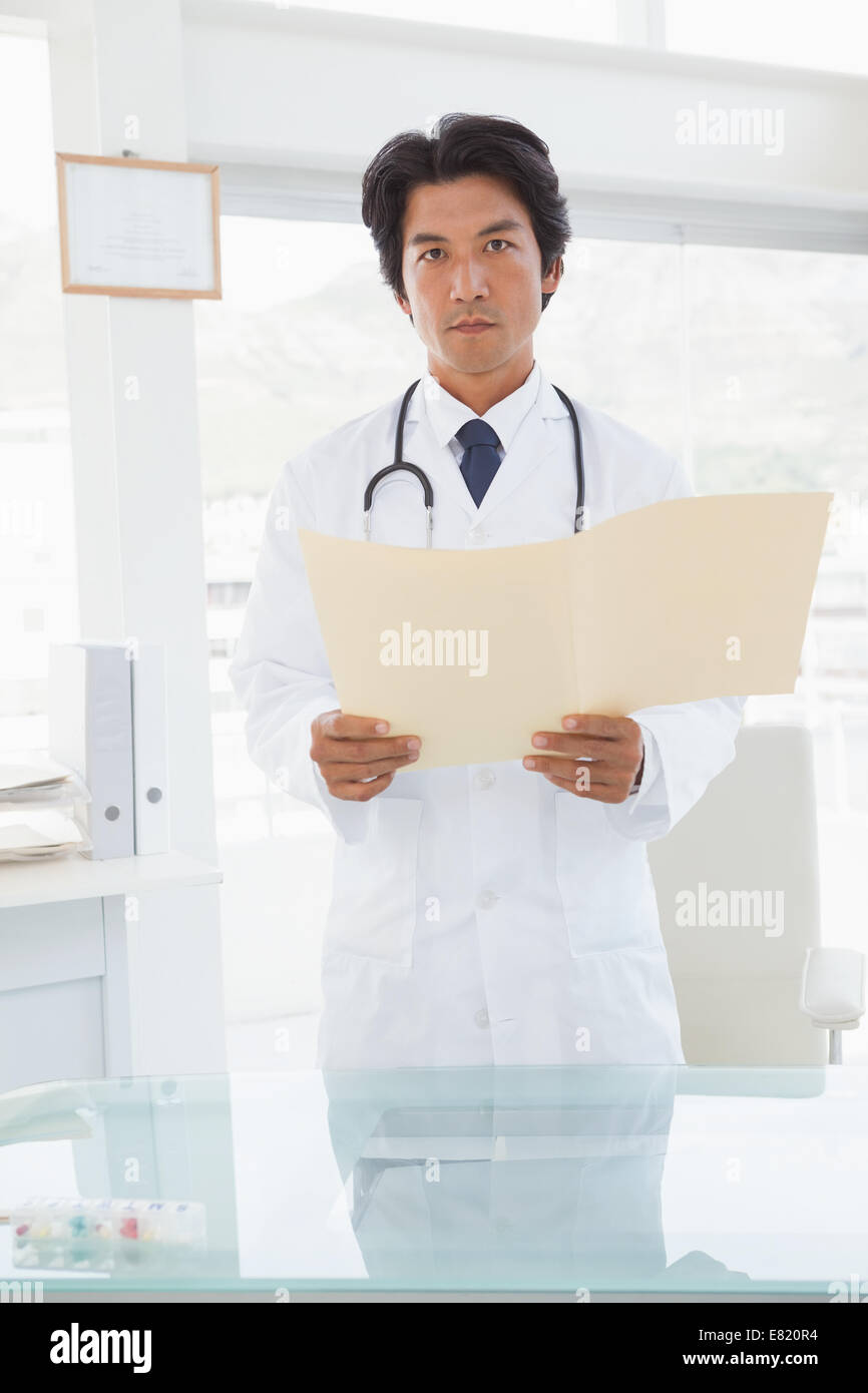 Serious looking doctor with medical files Stock Photo - Alamy