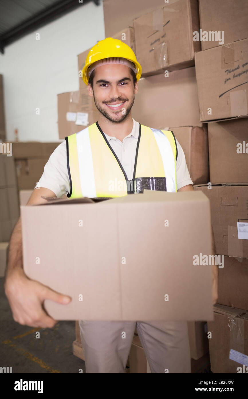 Worker carrying box in warehouse Stock Photo - Alamy