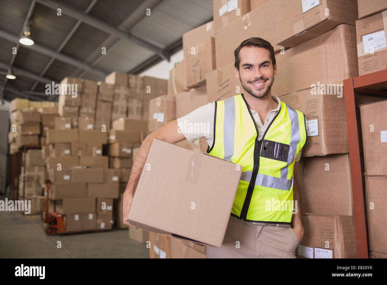 Worker carrying box in warehouse Stock Photo - Alamy