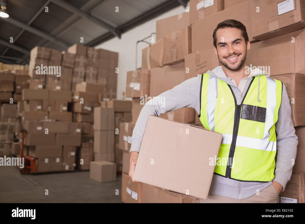 Worker carrying box in warehouse Stock Photo - Alamy