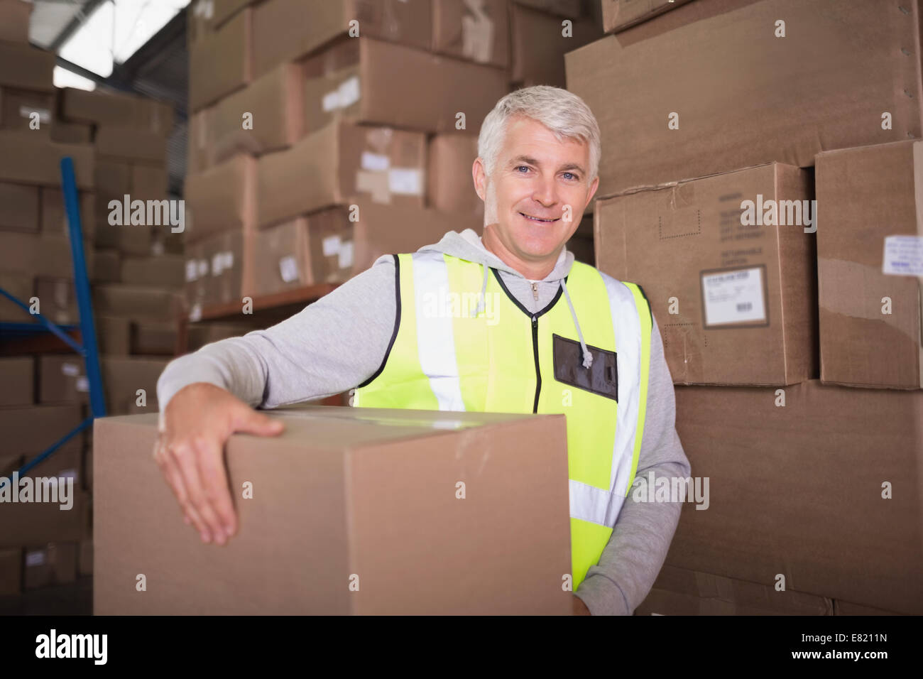 Worker carrying box in warehouse Stock Photo - Alamy