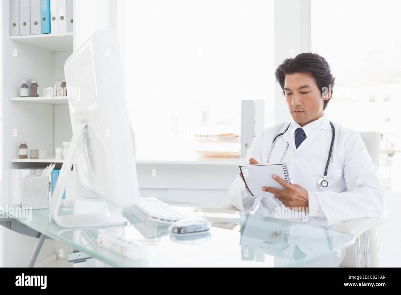 Serious doctor writing down some notes Stock Photo - Alamy