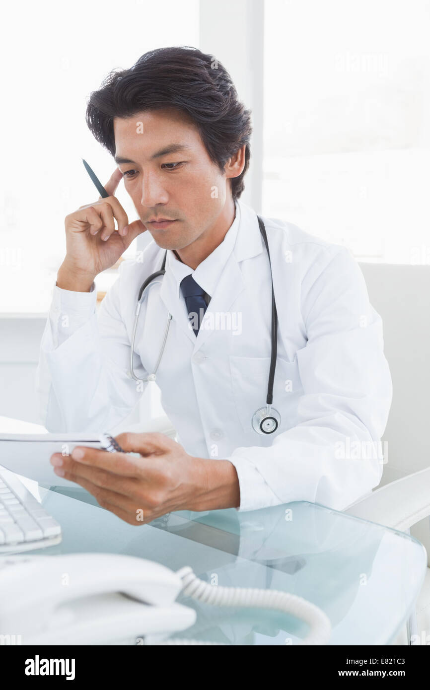 Serious looking doctor reading notes Stock Photo - Alamy