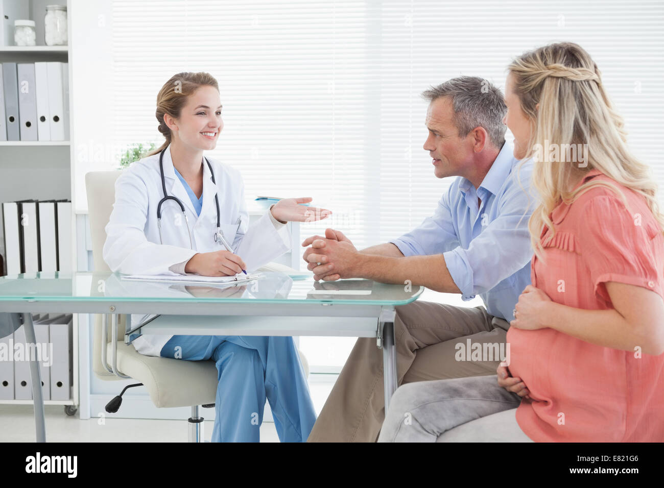 Happy couple talking to doctor Stock Photo - Alamy