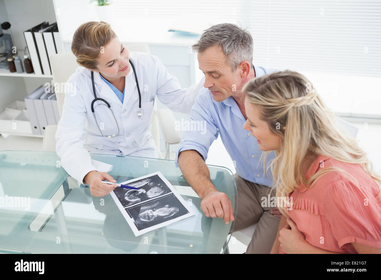 Happy couple talking to doctor Stock Photo - Alamy