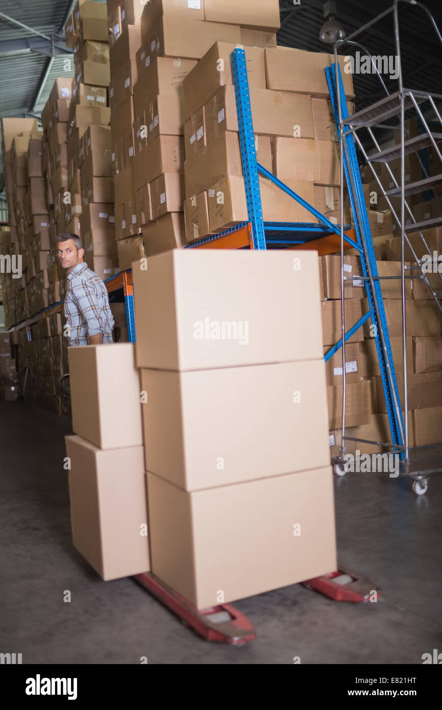 Worker pulling trolley with boxes in warehouse Stock Photo - Alamy