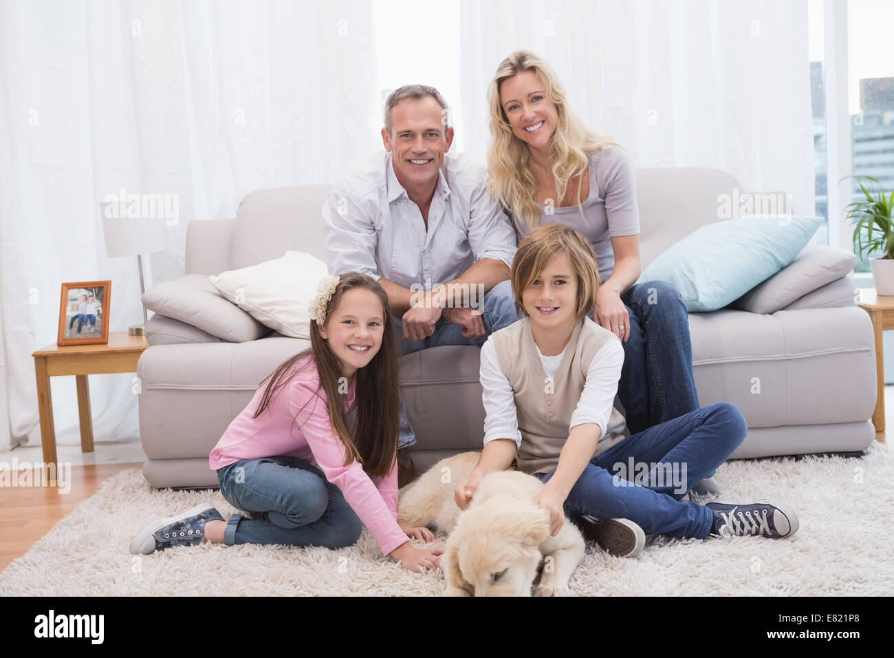 Smiling family with their pet yellow labrador on the rug Stock Photo ...