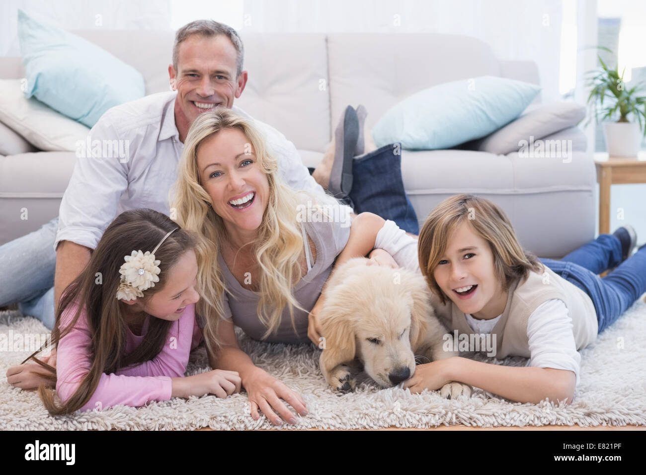 Laughting family with their pet yellow labrador on the rug Stock Photo ...