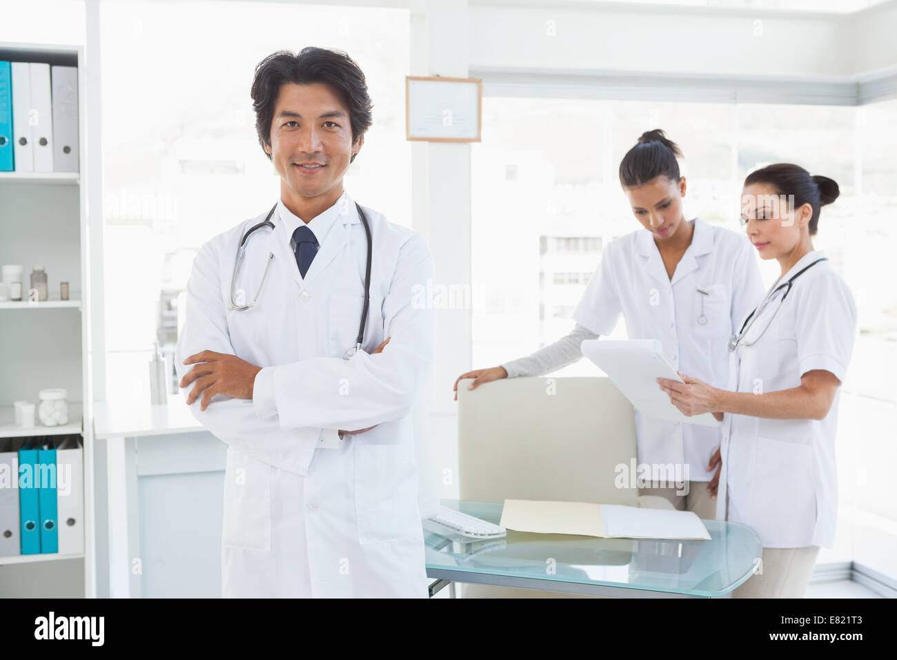 Doctor smiling in front of work colleagues Stock Photo - Alamy