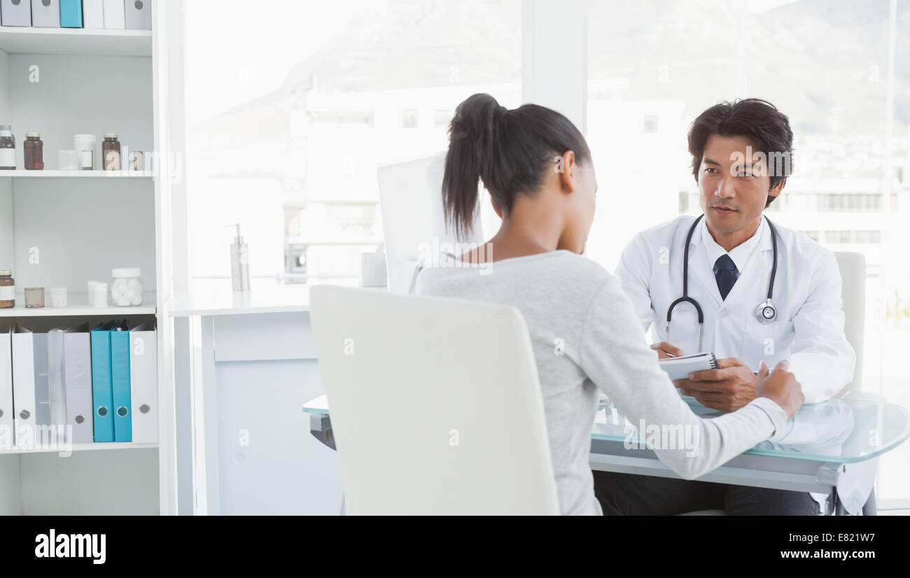 Doctor taking notes from patient Stock Photo - Alamy