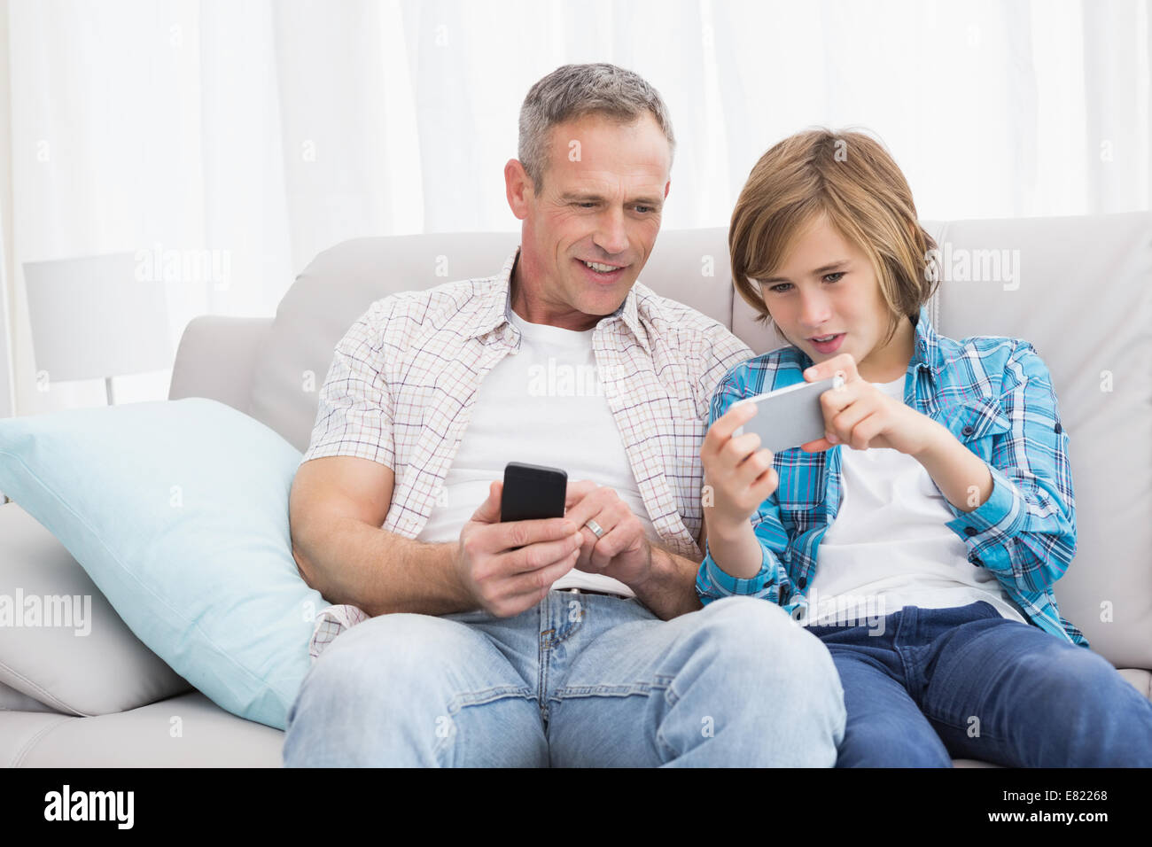 Son showing something on his mobile phone to his father Stock Photo - Alamy