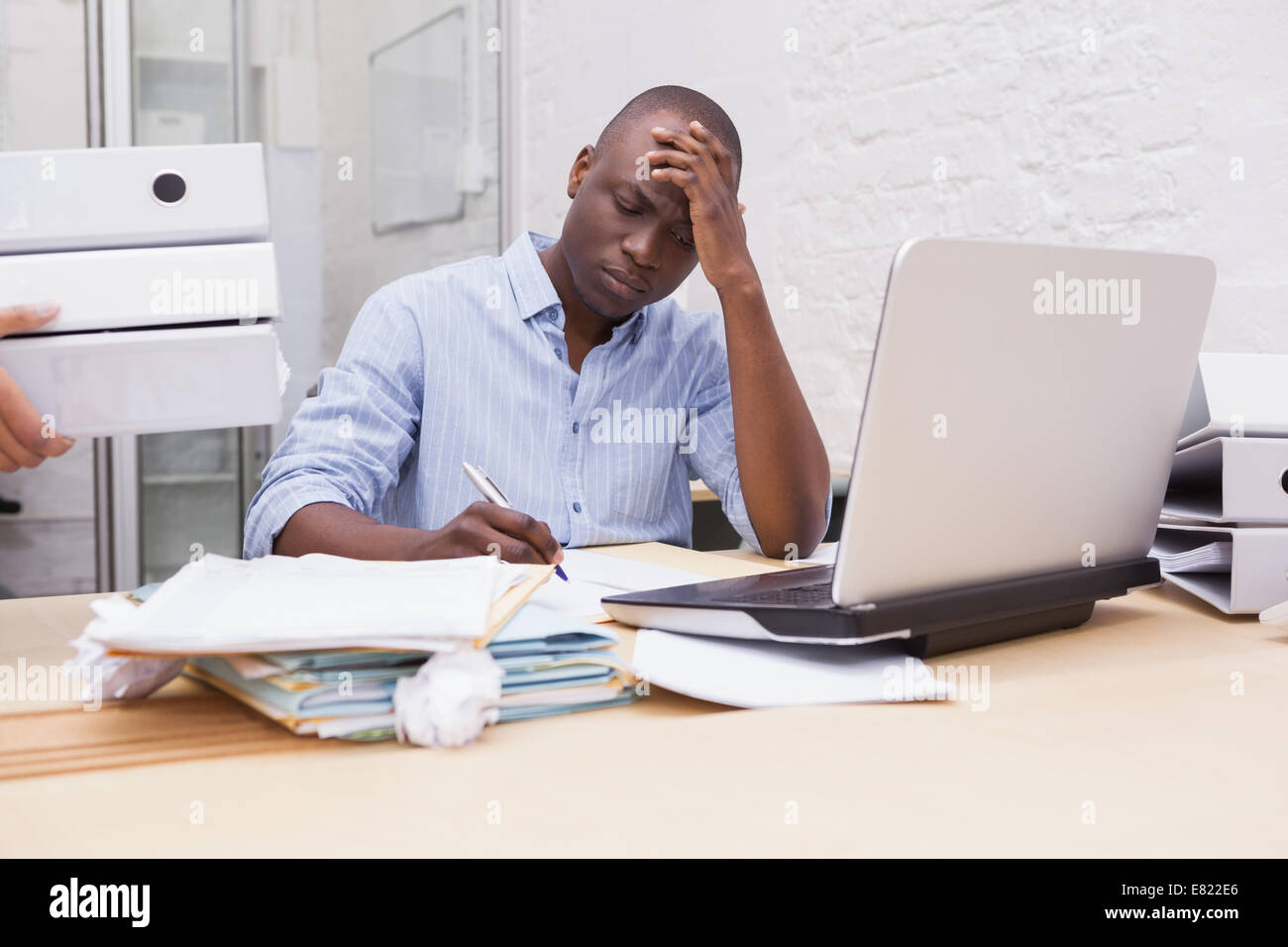 Annoyed businessman taking notes while holding his head Stock Photo - Alamy