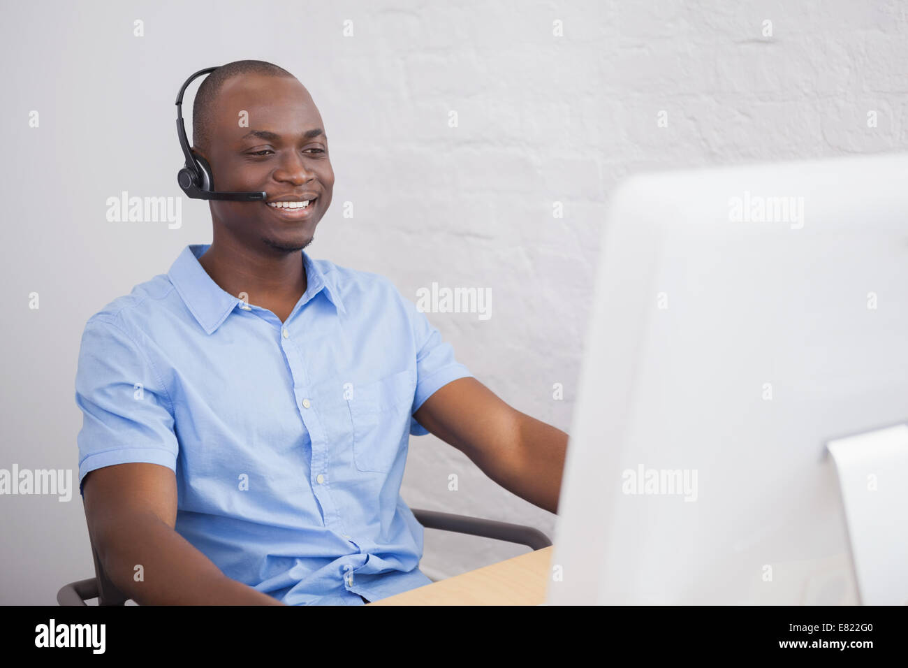 Businessman wearing headset while using computer Stock Photo - Alamy