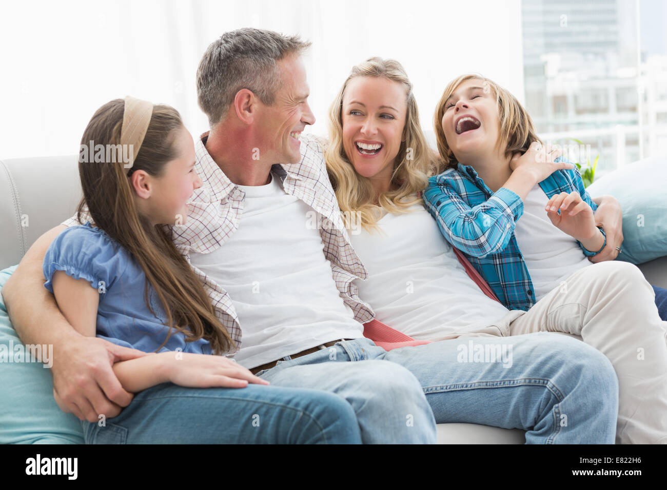 Smiling parents and children sitting together on couch Stock Photo - Alamy