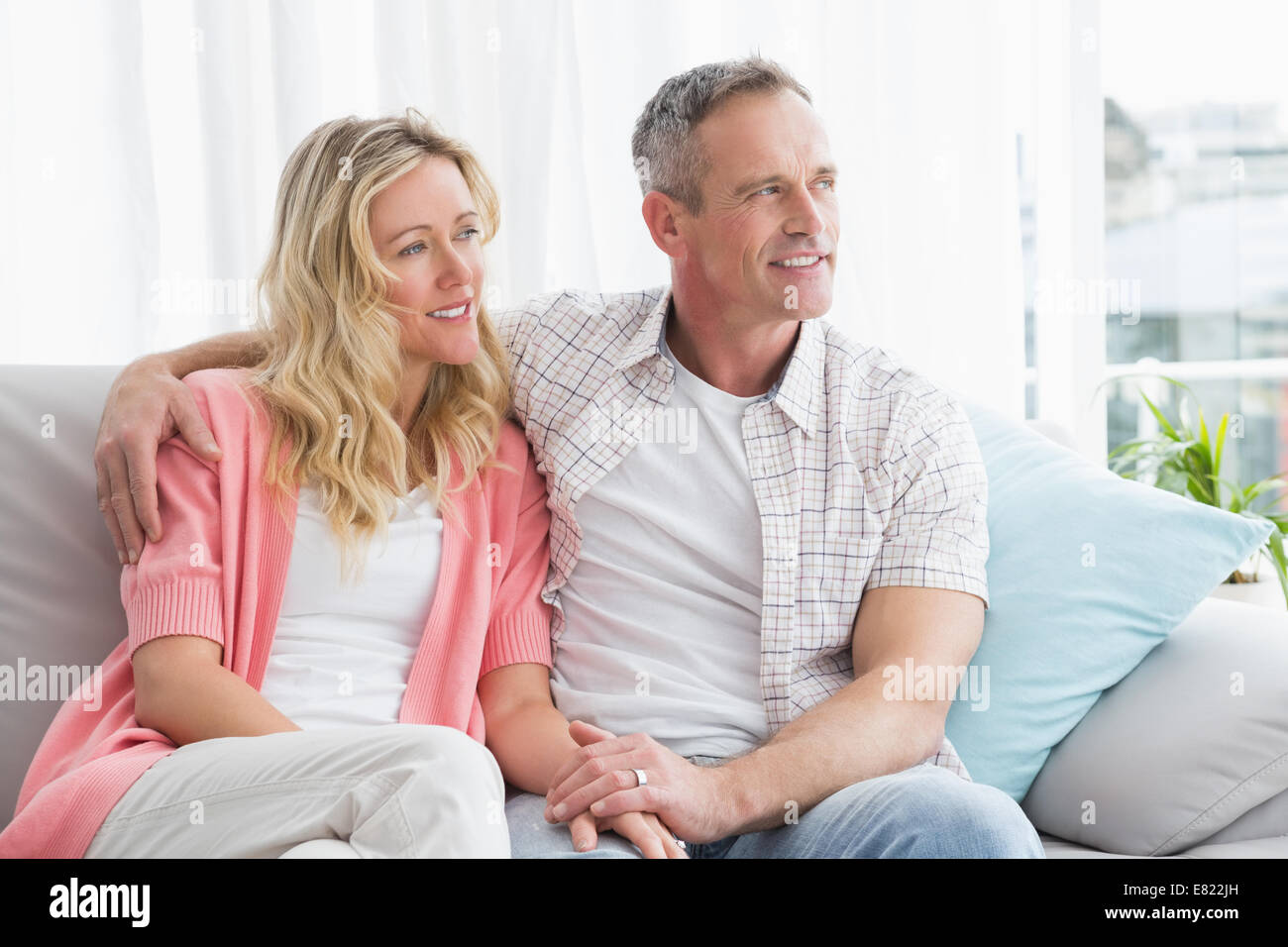 Smiling couple relaxing on the couch Stock Photo - Alamy