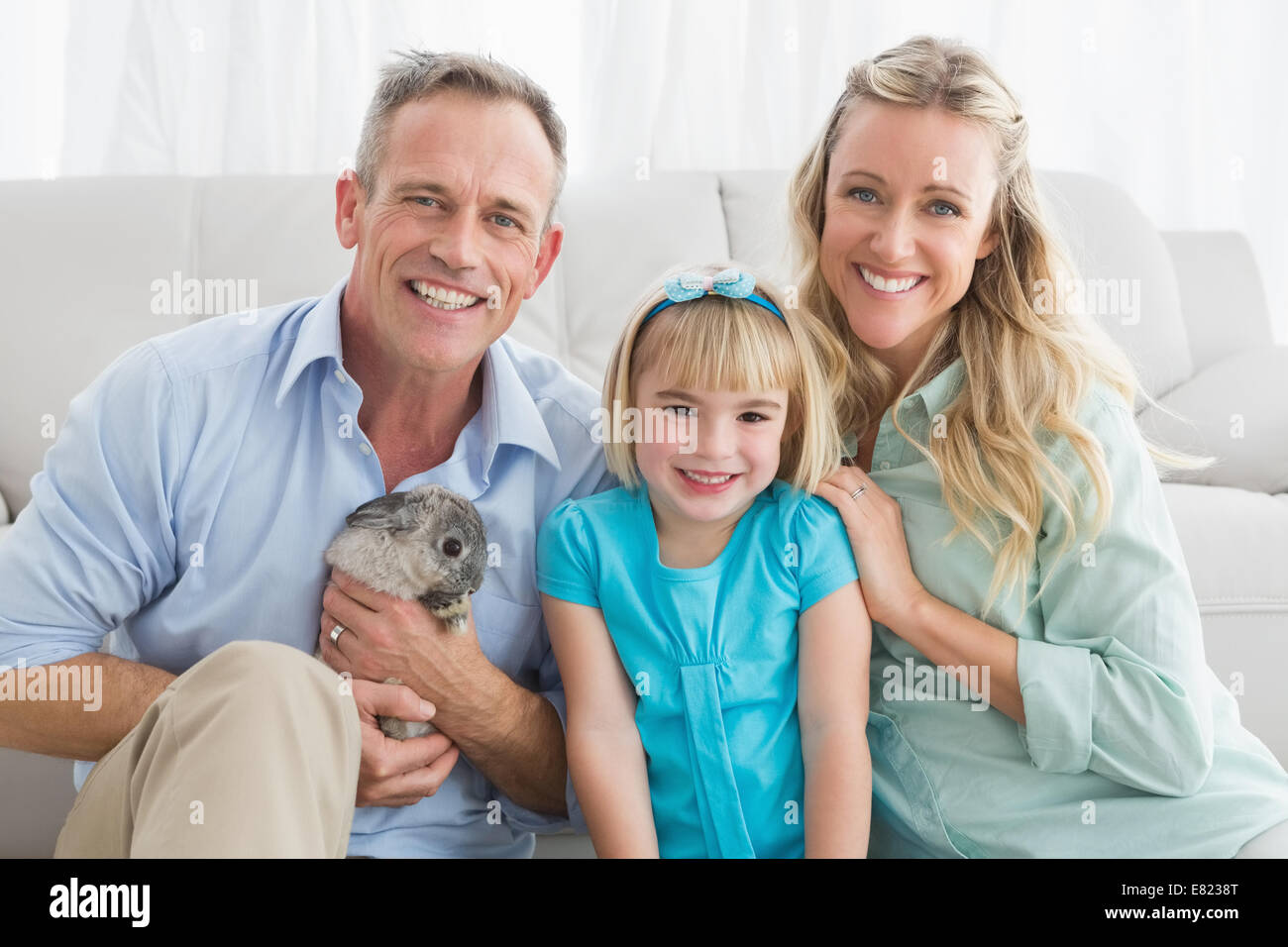 Smiling parents and daughter sitting with rabbit together Stock Photo ...