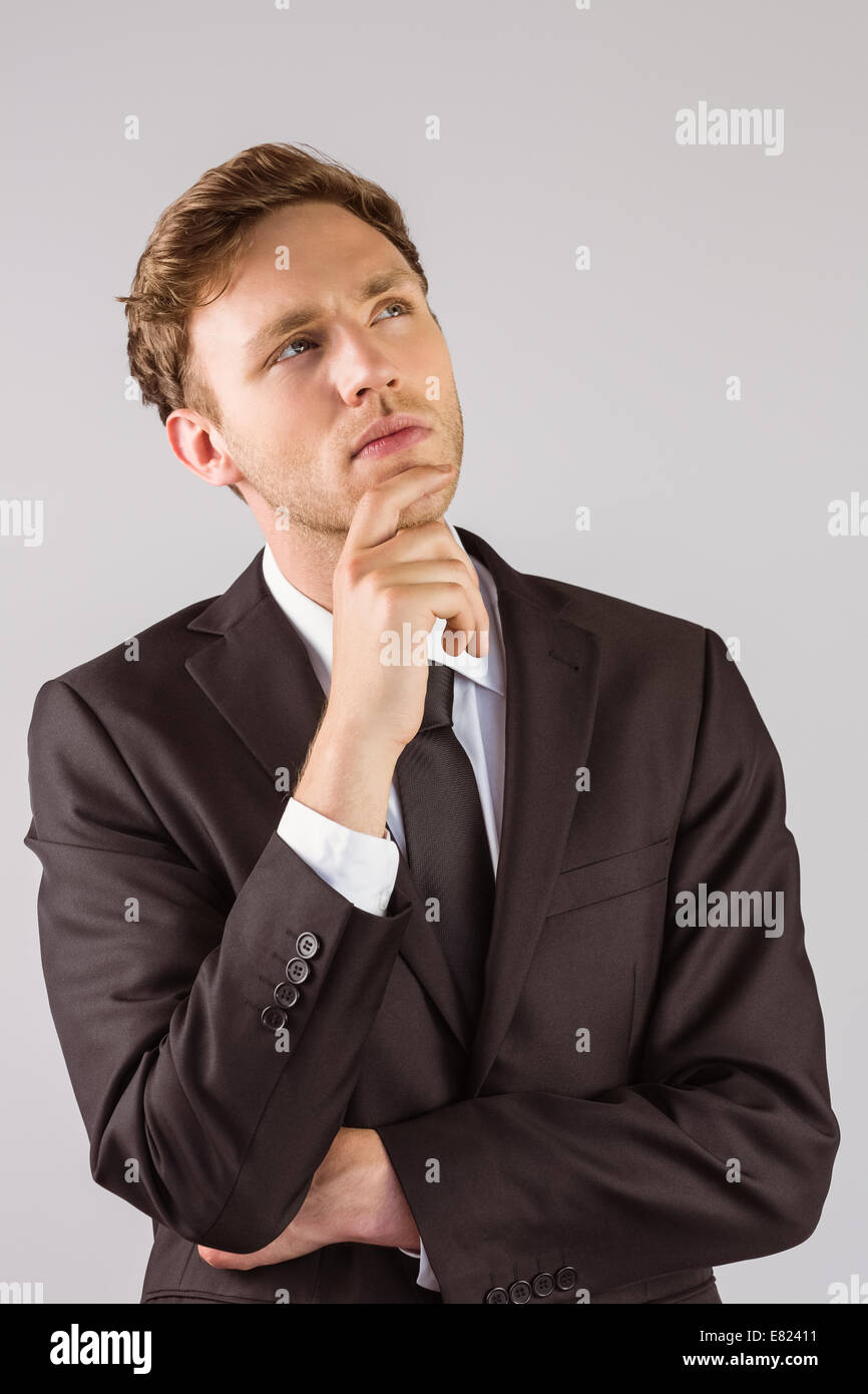 Young businessman thinking with hand on chin Stock Photo - Alamy
