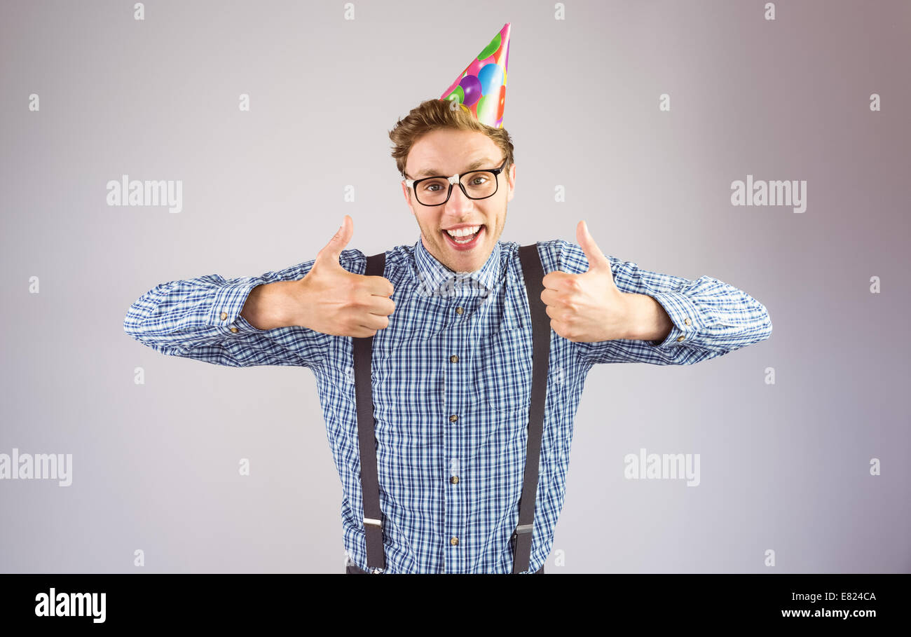 Geeky hipster wearing party hat smiling at camera Stock Photo - Alamy