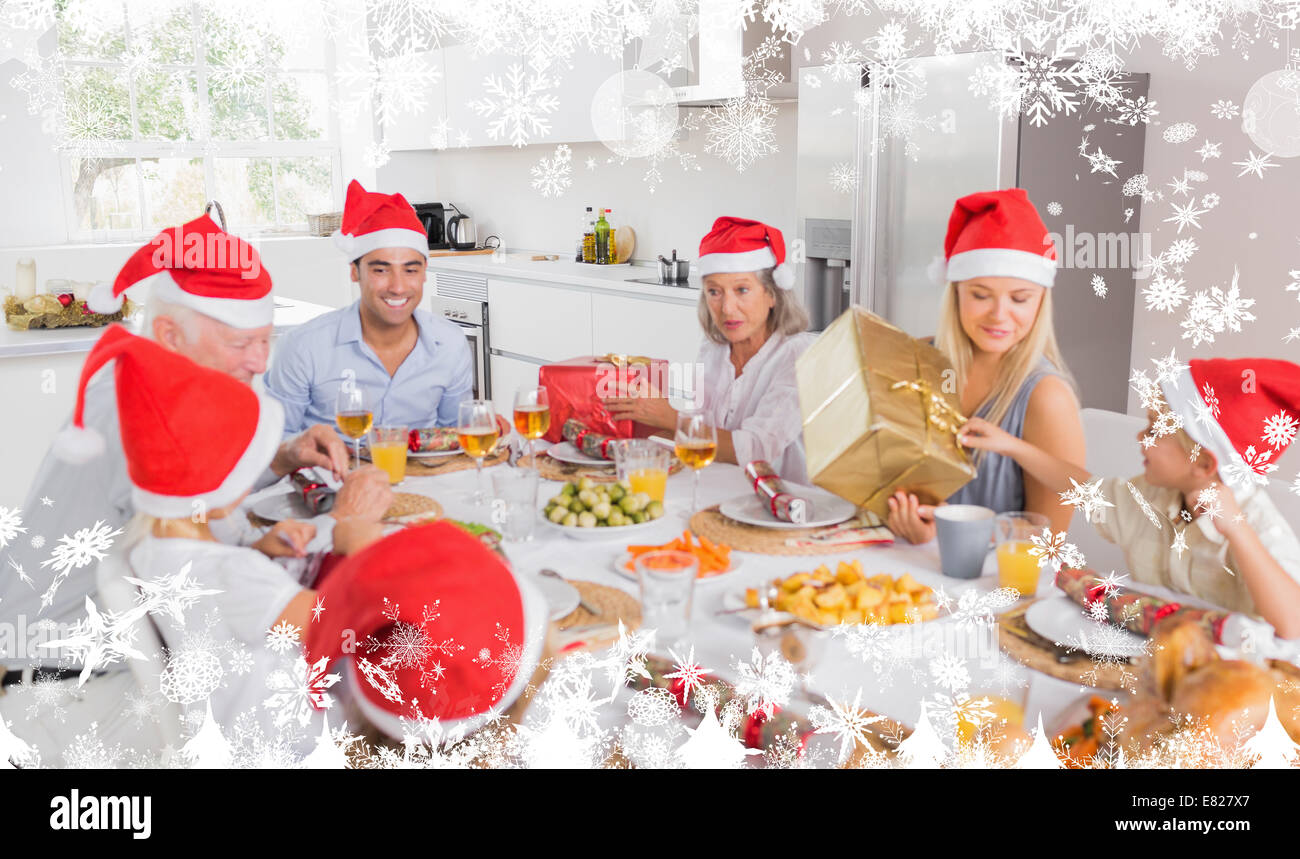 Composite image of smiling family around the dinner table at christmas ...