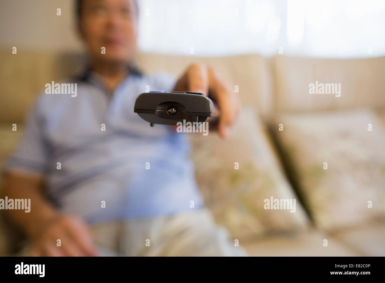 Man sitting on sofa holding remote control Stock Photo - Alamy