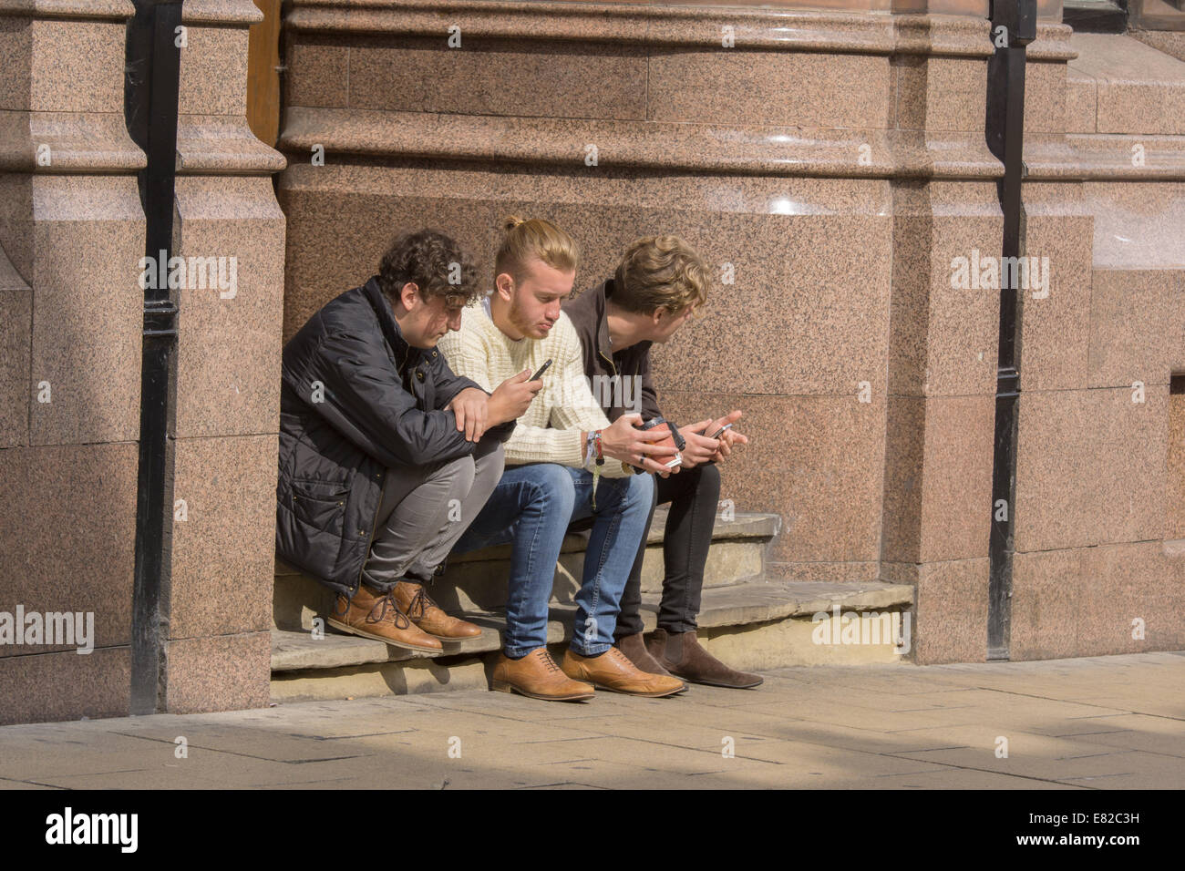 Three young men sitting on steps in a York street Stock Photo - Alamy