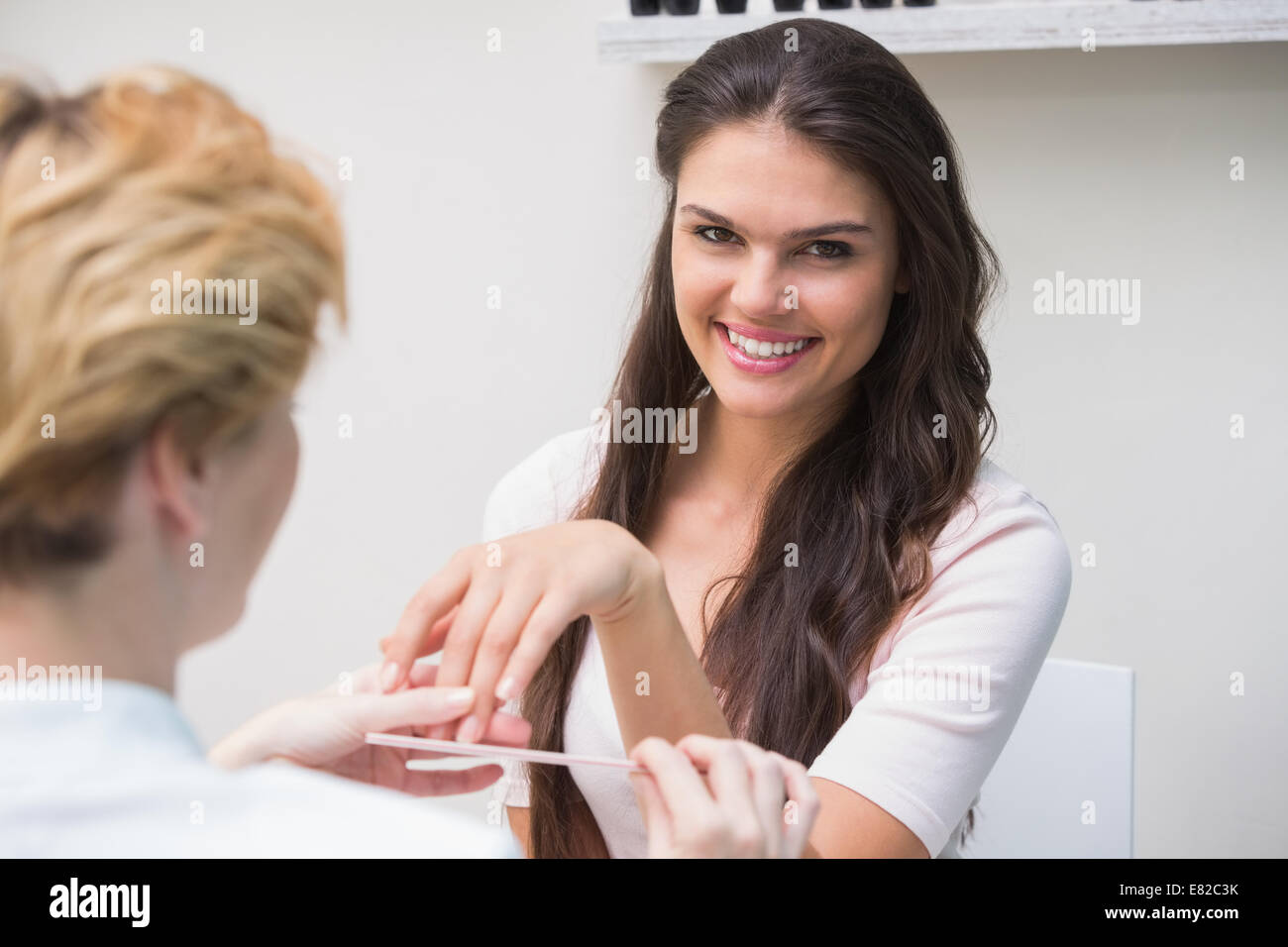 Pretty nail technician giving manicure to customer Stock Photo - Alamy