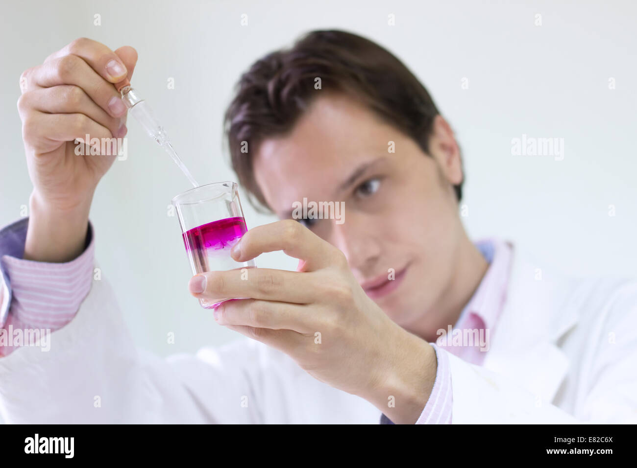 Scientist in a laboratory performing an experiment, mixing colorful ...