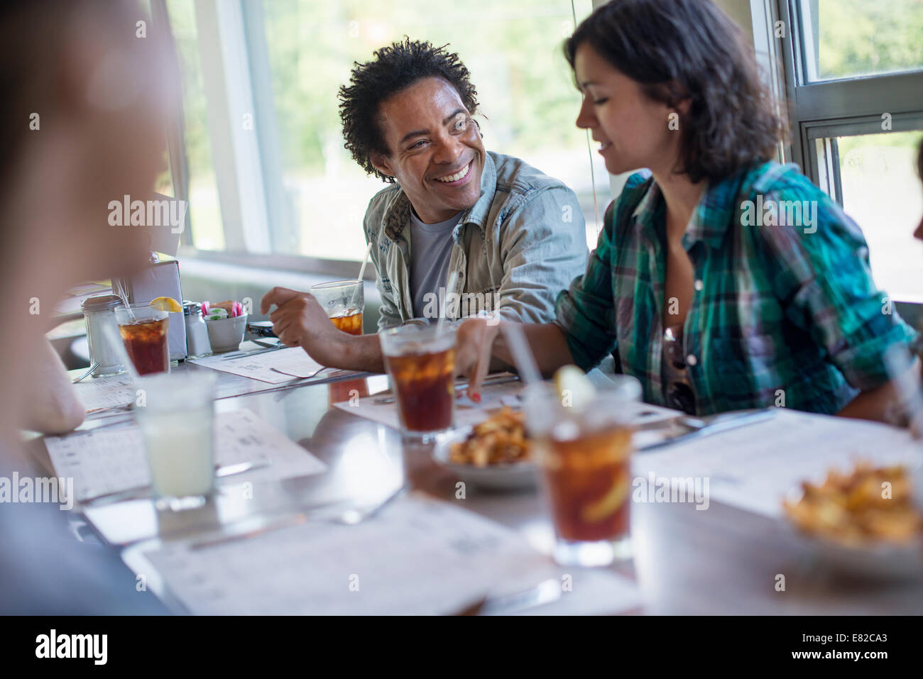 A group of friends eating at a diner. A couple seated side by side ...