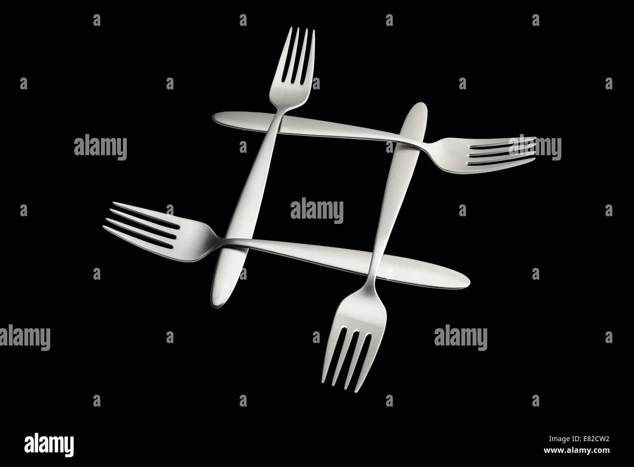 Four interlaced silver forks on black background - clipping path Stock ...