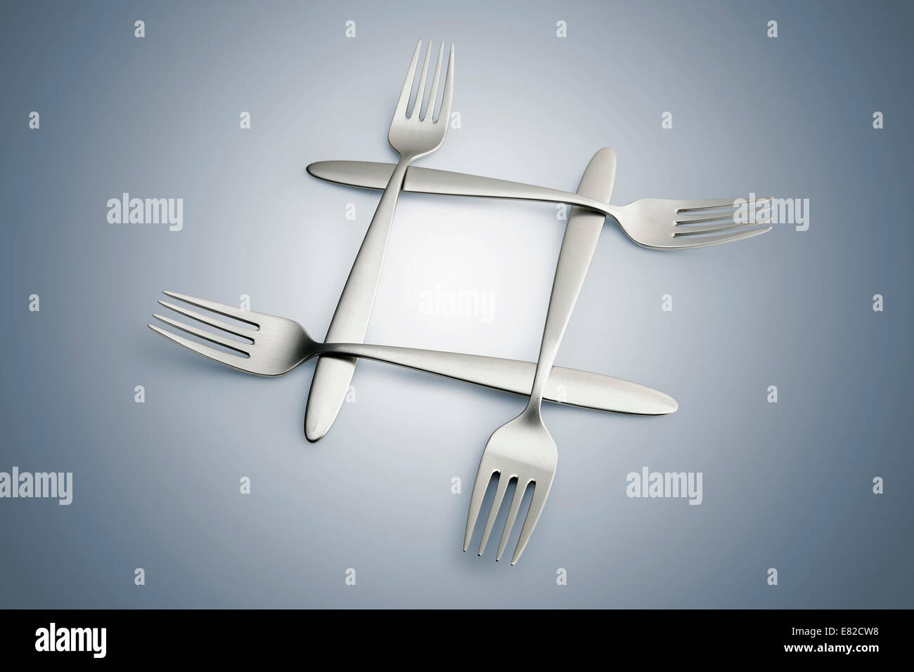 Four interlaced silver forks on blue gradient background - clipping ...