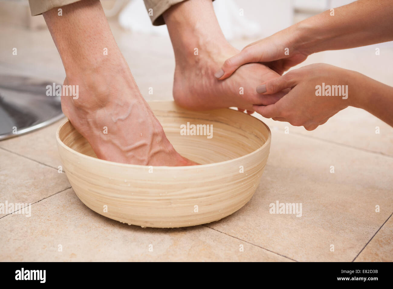 Pedicurist cleansing customer feet Stock Photo - Alamy