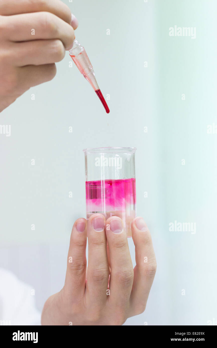 Scientist in a laboratory performing an experiment, mixing colorful ...