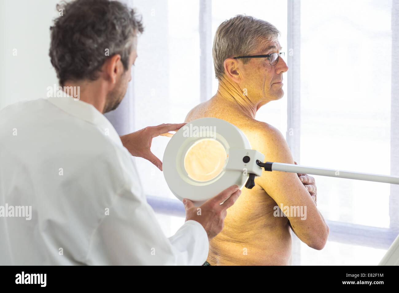 Doctor examining the skin of a man Stock Photo - Alamy