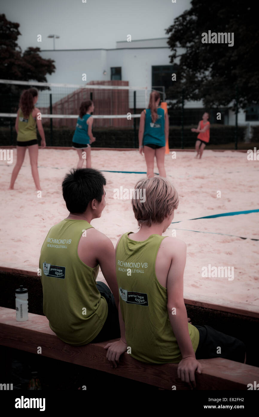 Two young people wait on the bench for their turn to play on a park ...