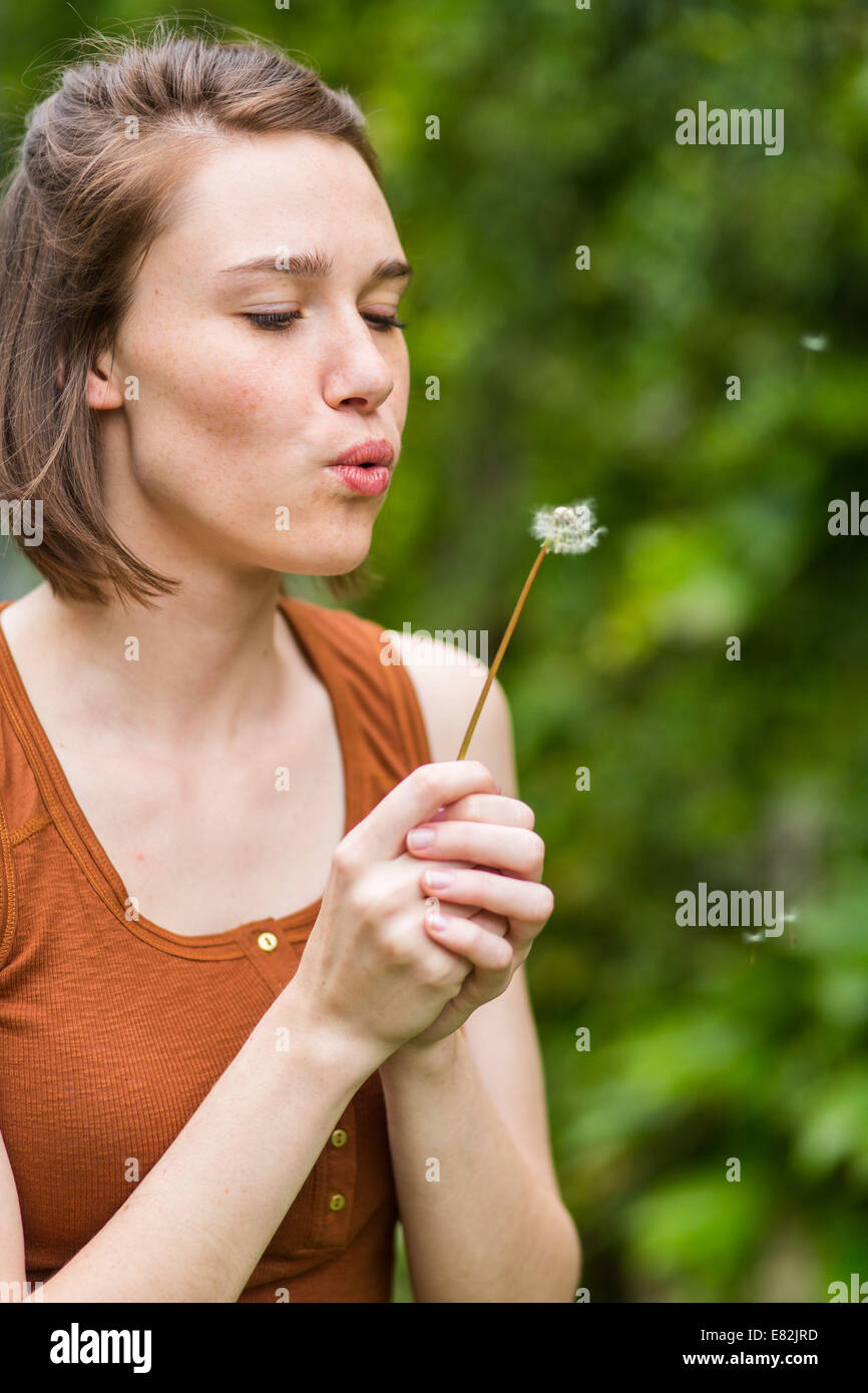 Woman blowing on a dandelion flower Stock Photo - Alamy
