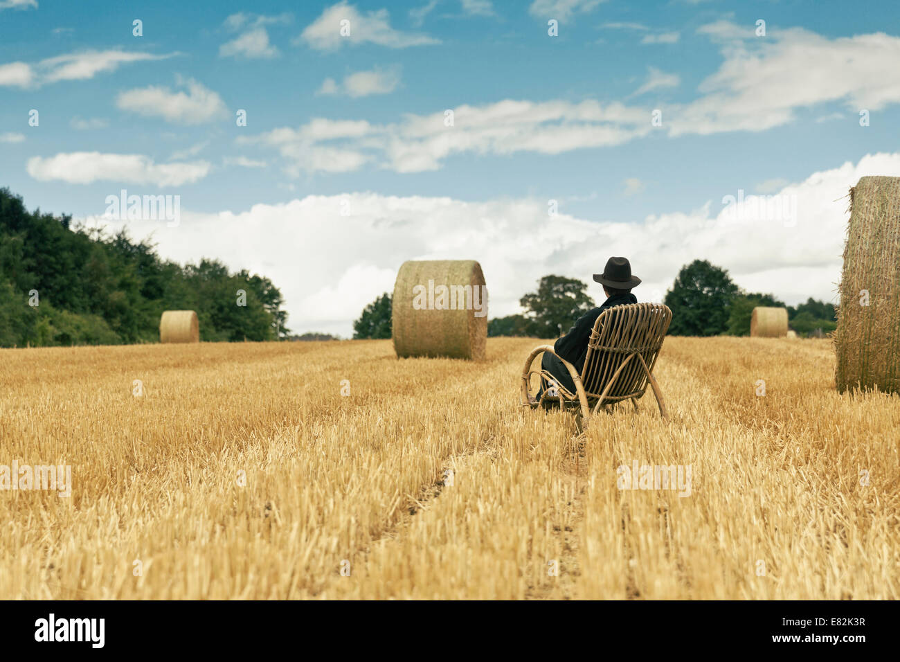 Teenage boy with hat sitting in a rocking chair on a grainfield Stock ...